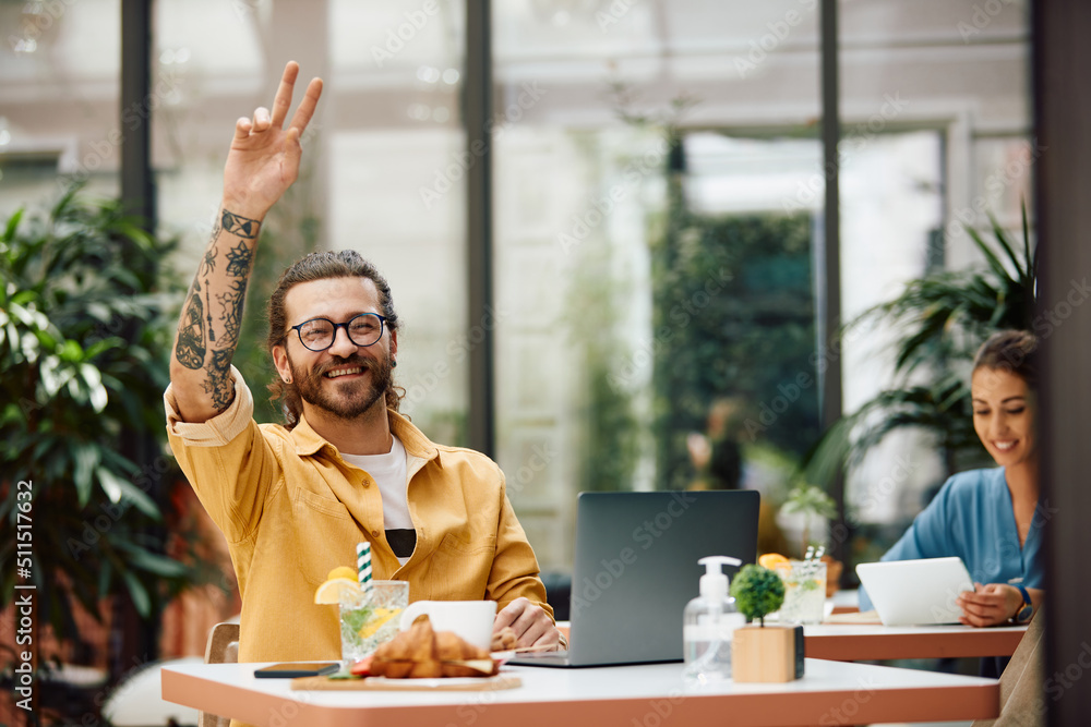 Happy man raising his hand to call waiter to take his order in cafe ...
