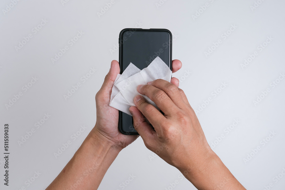 Hand wiping the mobile phone with the alcohol sanitiser wipes to clean ...
