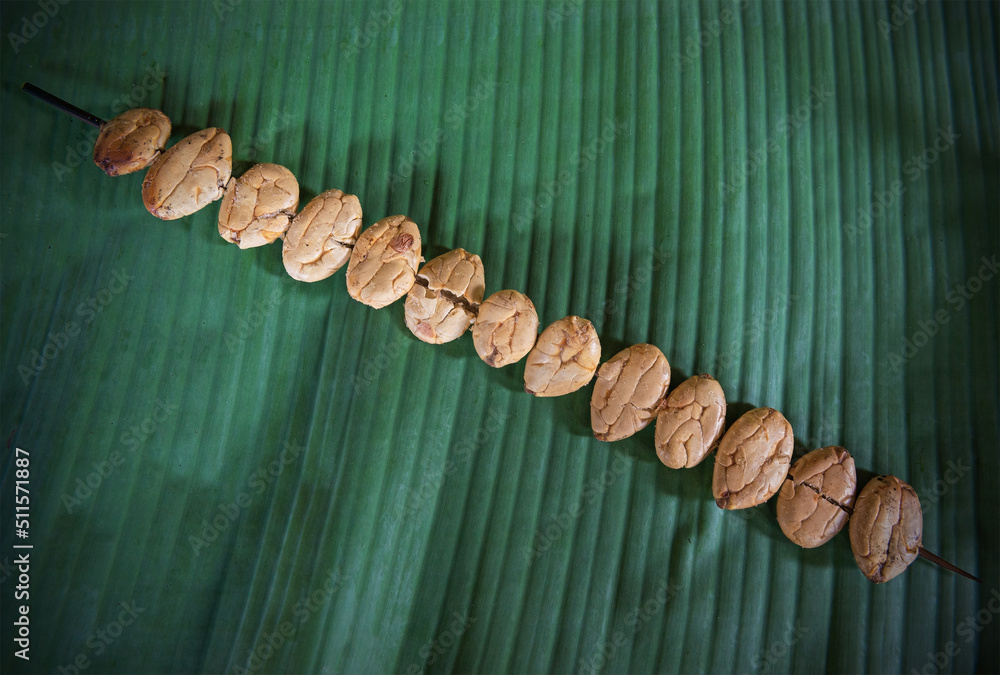 Grilled white cacao beans skewer on palm leaf is a traditional food in ...
