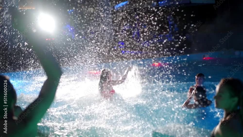 Friends have night pool party dancing in private villa swimming pool ...