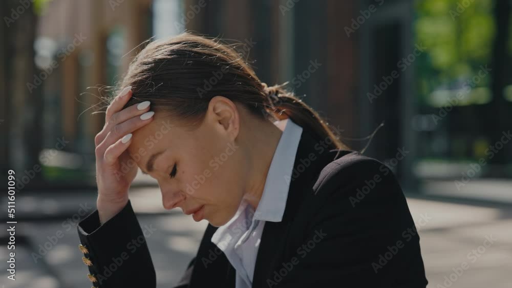 Desperate caucasian woman in formal clothes sitting outdoors near ...