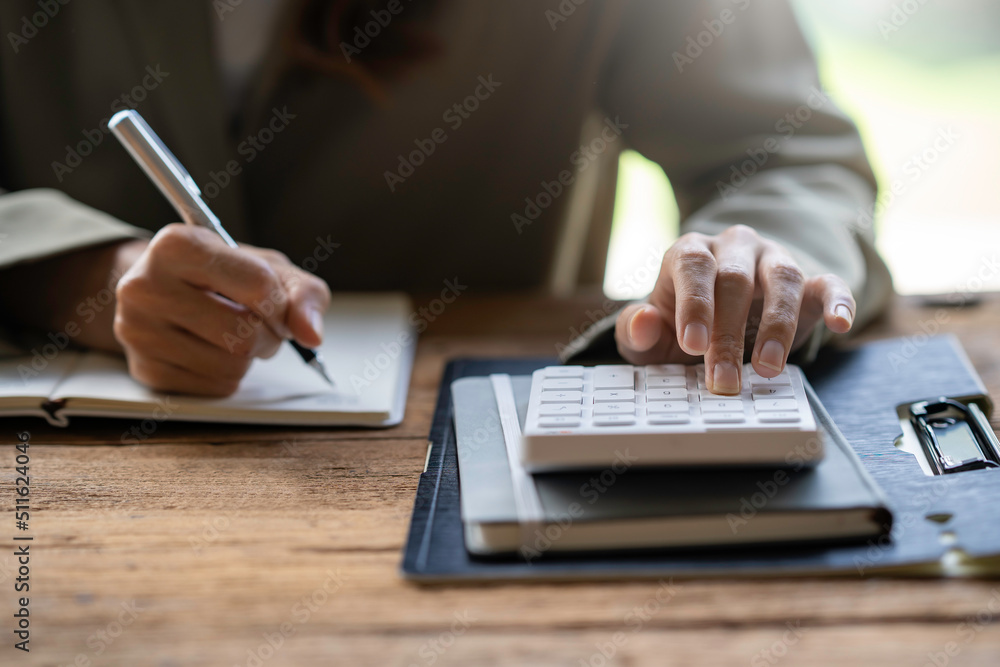 Businesswoman using calculator and laptop computer for analysis ...