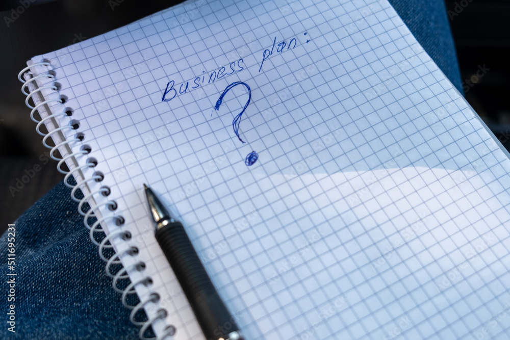 Business plan and question mark written on a notebook. Reflections on ...
