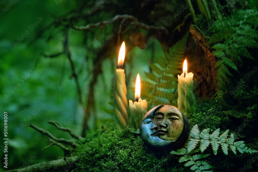 candles and symbolic moon amulet on dark forest background. pagan ...