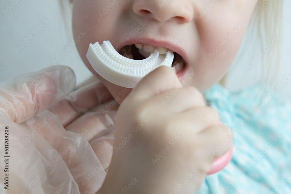 dentist, doctor teaches child, small patient to silicone brush capa his ...