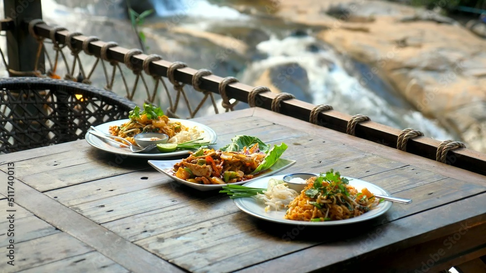 Traditional thai food in outdoor cafe with nature waterfall background ...