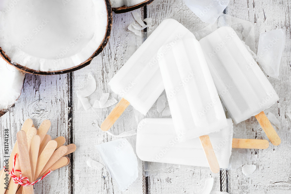 Coconut ice pops in a cluster. Above view table scene over a white wood ...
