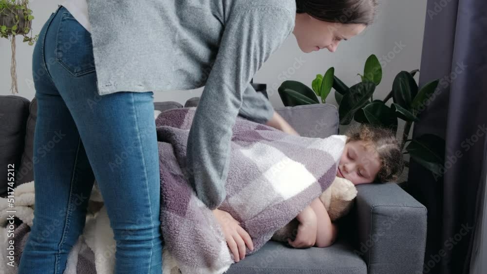 Caring mom covering sleepy little girl with blanket or plaid. Loving ...