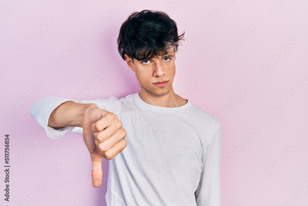 Handsome hipster young man wearing casual white shirt looking unhappy ...