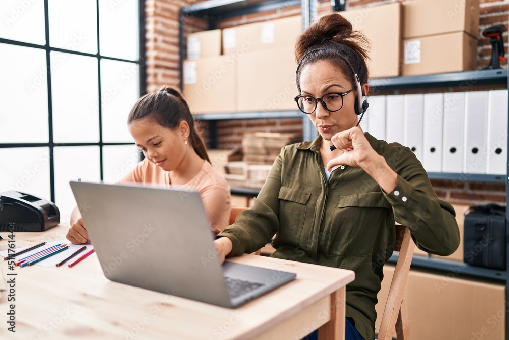 Young mother and daughter working at the office and doing homework with ...