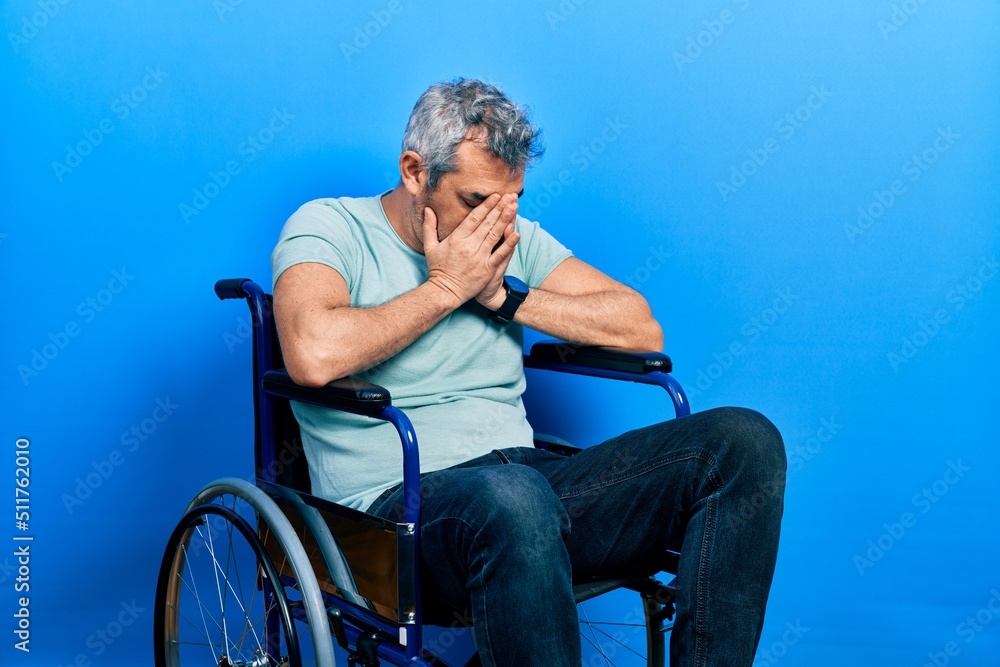 Handsome middle age man with grey hair sitting on wheelchair with sad ...