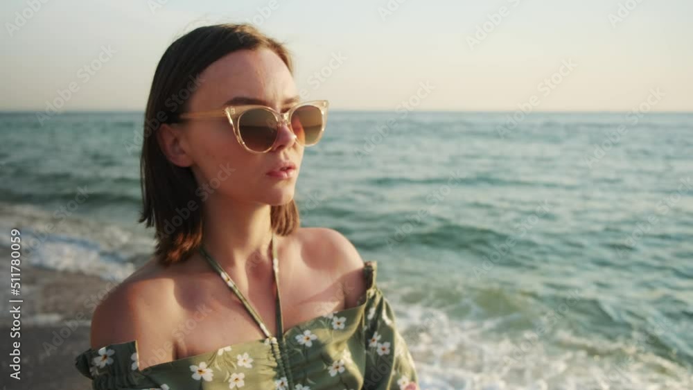 Woman wearing sunglasses. Girl enjoying walk along sea shore. Carefree ...