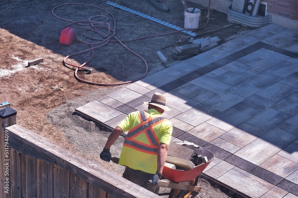 Selective focus of construction worker working on a backyard paver ...