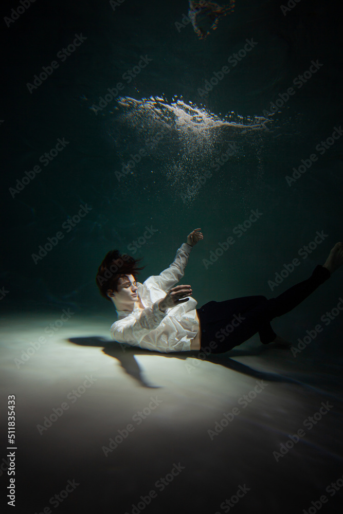 Sink. A young man is going to the bottom. A guy in a white shirt and ...