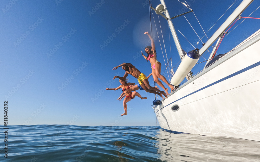 Multiracial friends jumping out of boat in the sea while having fun in ...
