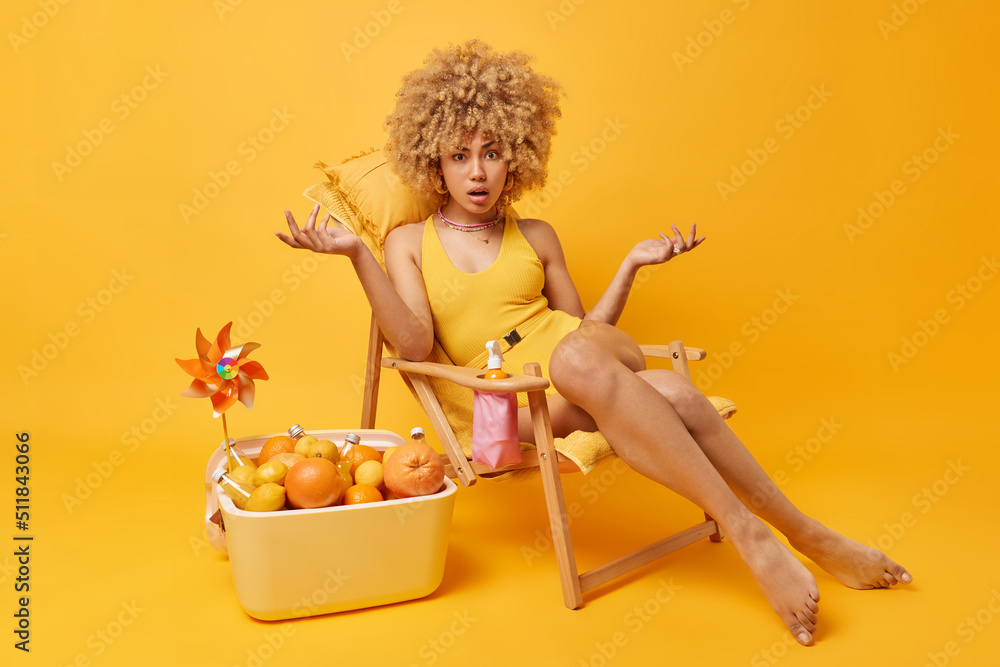 Horizontal shot of confused hesitant woman shrugs shoulders looks ...