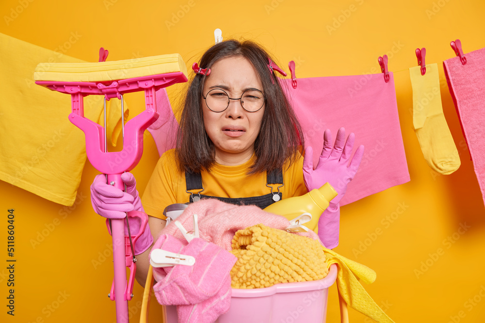 Housekeeping and cleaning service. Displeased Asian woman looks with ...