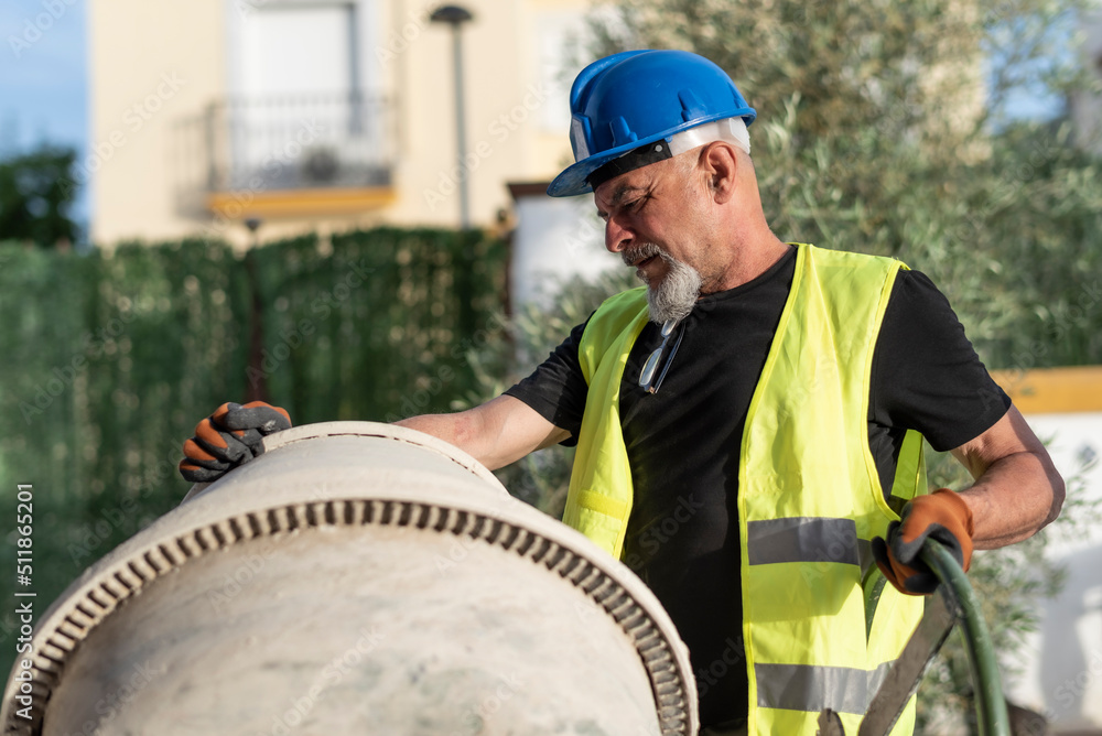 60-year-old outdoor construction worker, working in the concrete mixer ...
