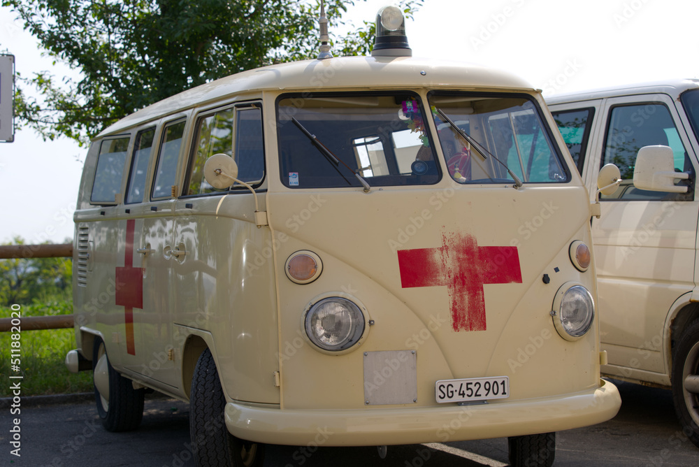 Ochre classic ambulance car VW Bus with red cross and blue light at car ...