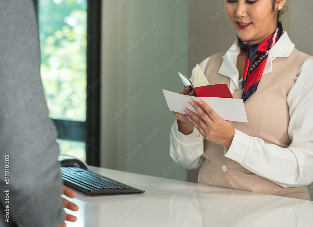 Smiling attendant working at check-in desk in airport. Female airline ...