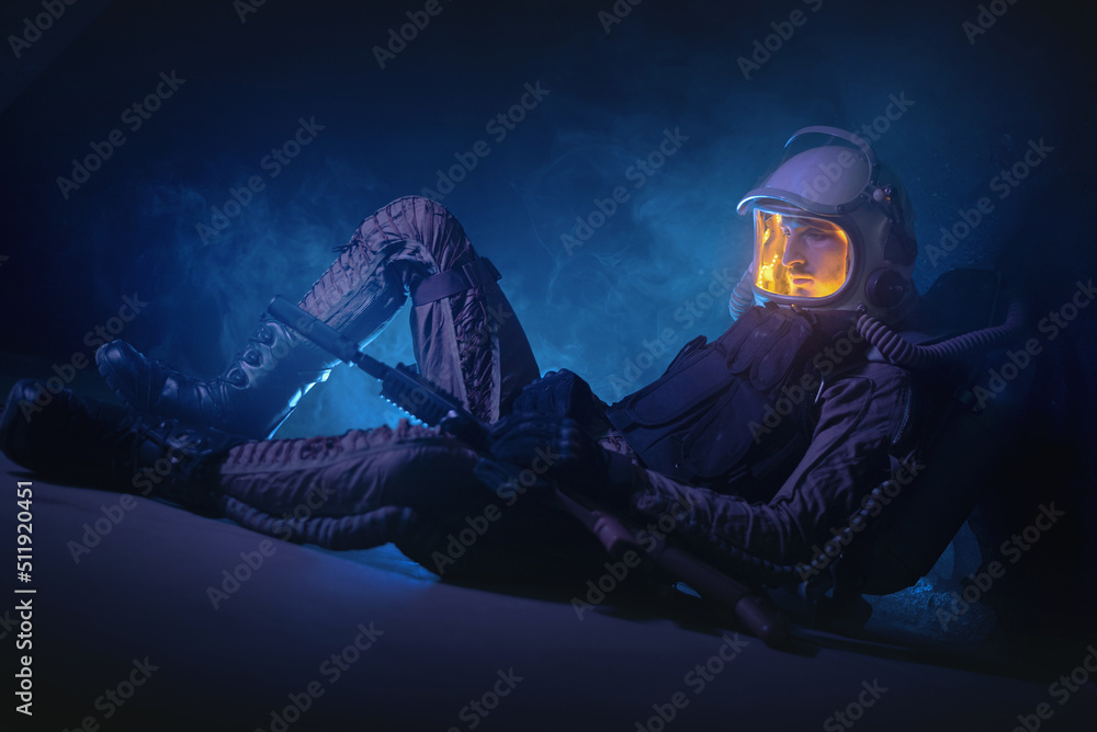 Spaceman or star trooper in the helmet and with rifle in the blue smoke ...