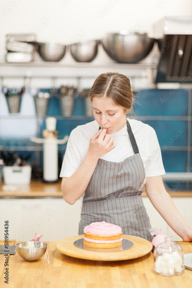 Female pastry chef making cake of sponge layers and cream. Confectioner ...