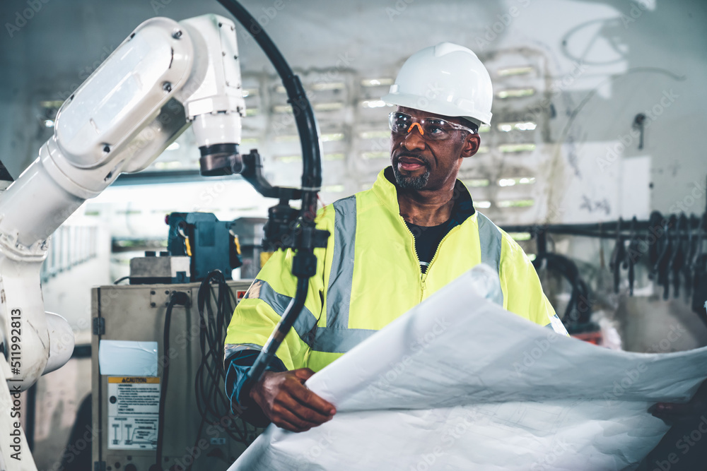 African American factory worker working with adept robotic arm in a ...