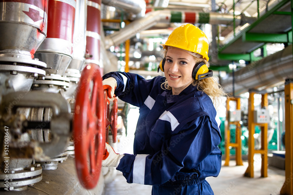 Portrait of female refinery worker working by pipeline and valves ...