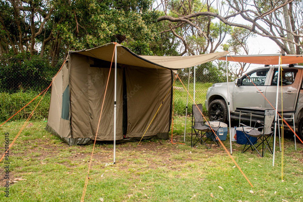 RV tent with attached awning setup at the campsite surrounding by ...