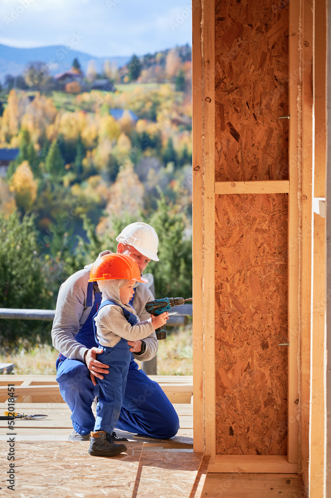 Father with toddler son building wooden frame house. Boy helping his ...