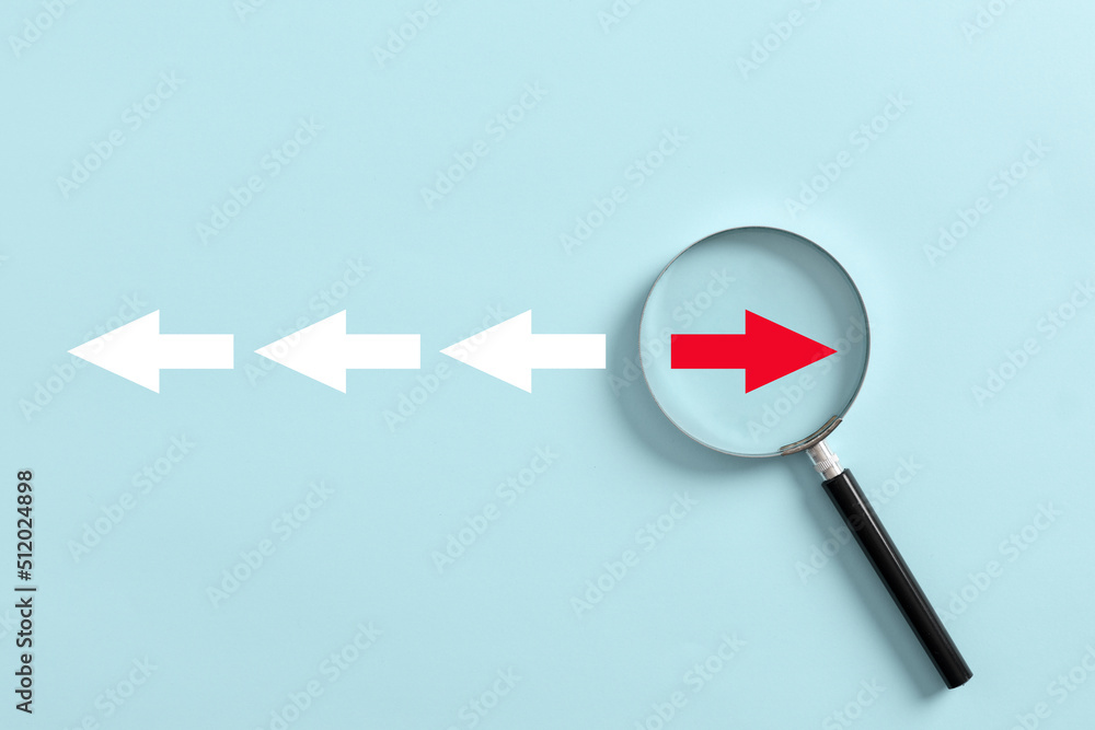Magnifying glass on red arrow facing the opposite direction of white ...