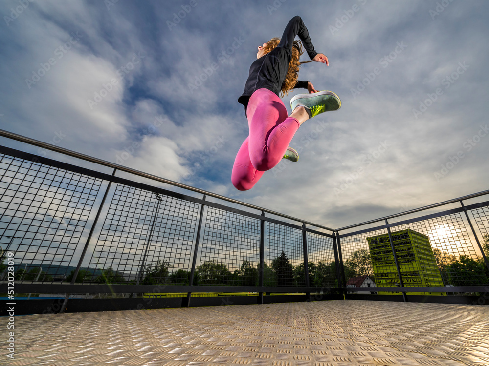 Young woman jumping in sports park at sunset Stock Photo | Adobe Stock