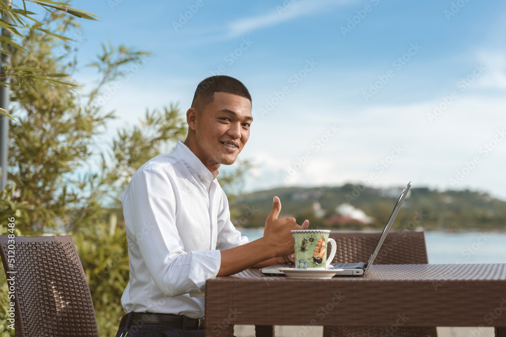 A Filipino male data analyst giving the thumbs up sign while working ...