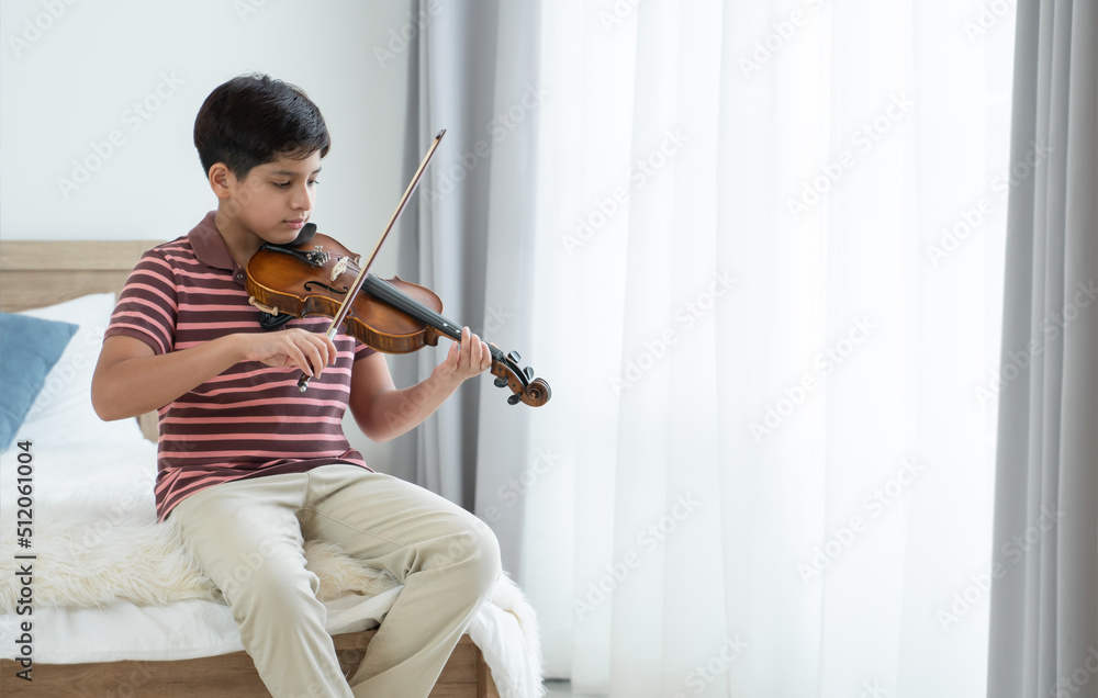Indian handsome kid is actively practicing playing wooden violin at ...