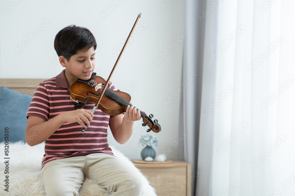 Indian handsome kid is actively practicing playing wooden violin at ...