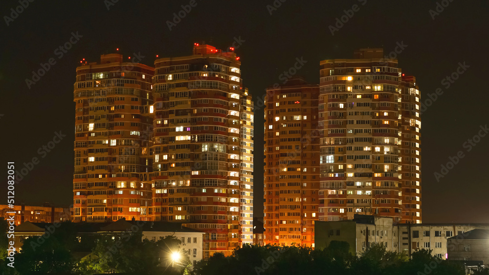 Foto de A multistory apartment building with glowing windows at night ...