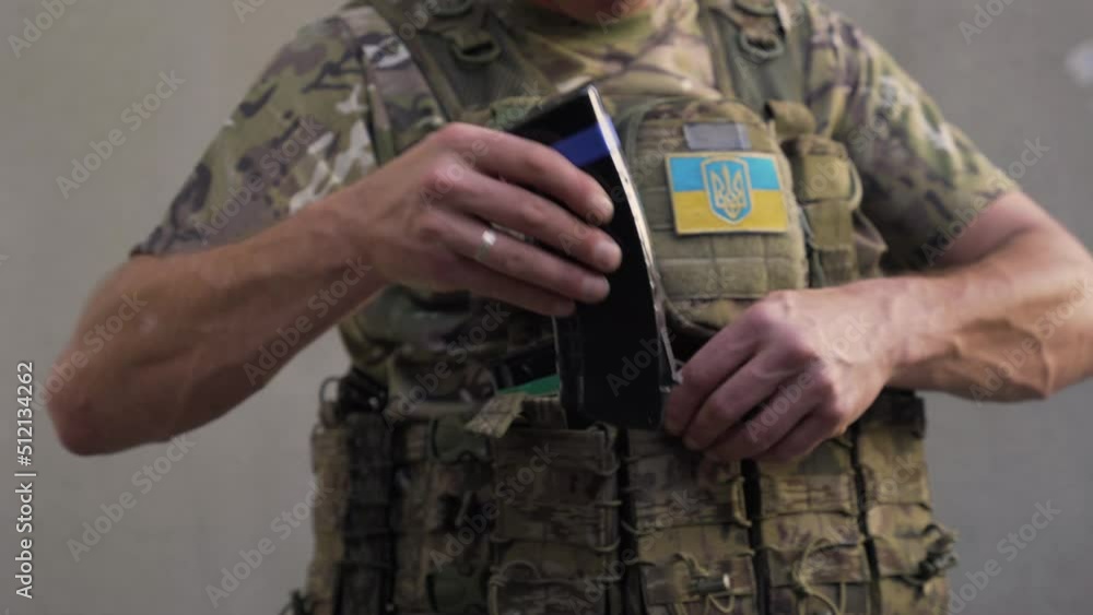 Ukrainian military man in combat camouflage and body armor puts a ...