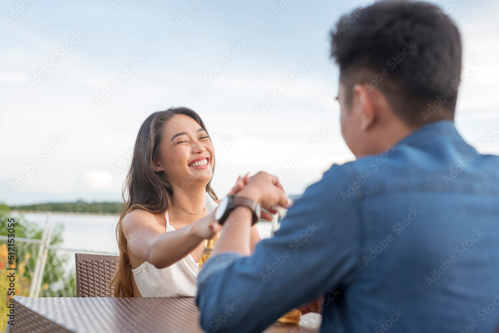 A young asian woman chuckles and holds her dates hand after being ...