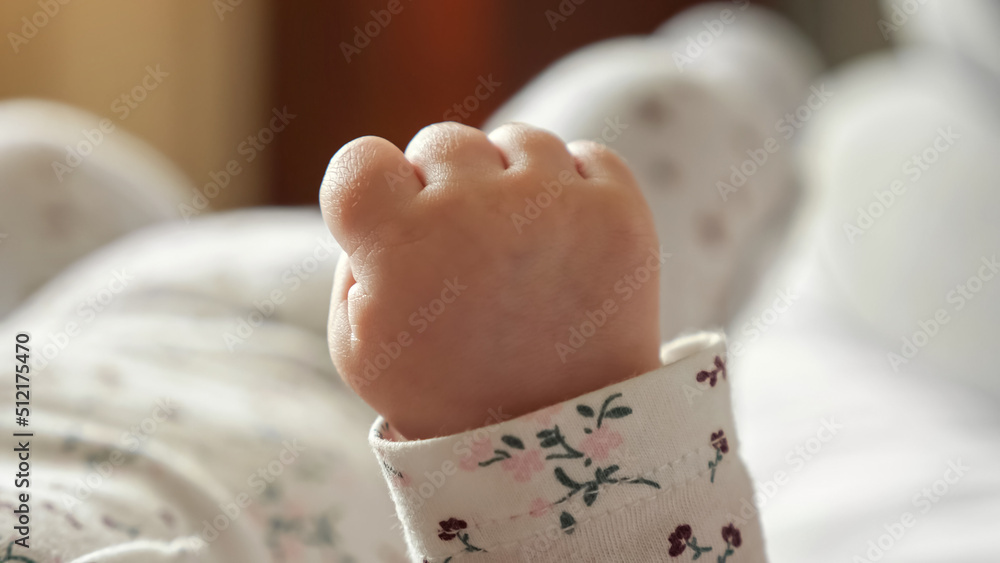 Tiny hand of newborn baby clenched into fist on blurred background in ...