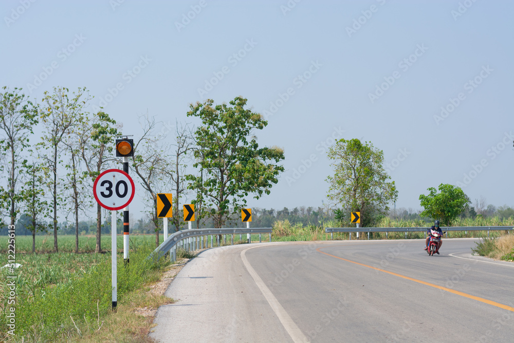 30 mph maximum speed limit sign and Curve warning sign on a road in a ...