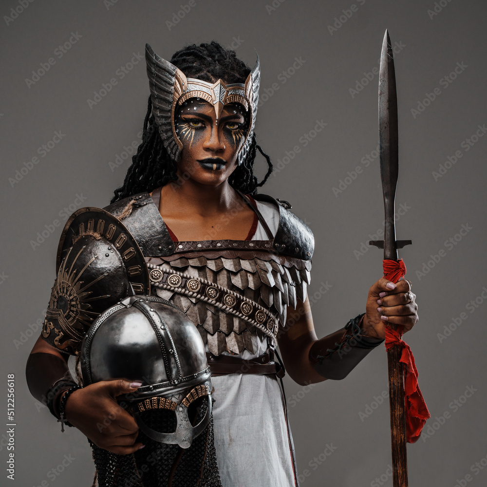 Shot of strong black woman dressed in ancient armor holding spear and ...