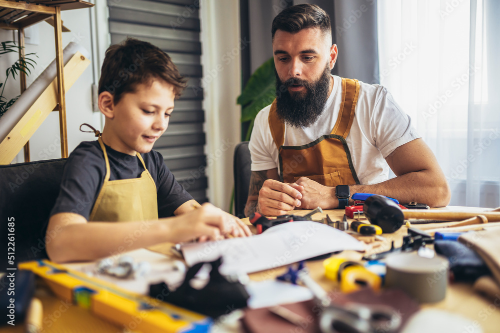 Father teaches his son to plan wood in a carpentry workshop. Hobby and ...