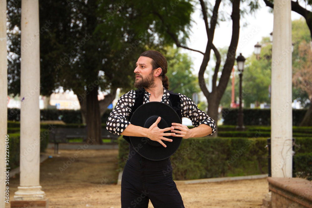 gypsy man dancing flamenco with long hair and beard in a park next to ...