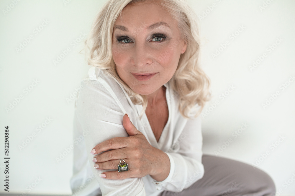 Portrait of a beautiful woman aged 60, dressed in a white shirt ...