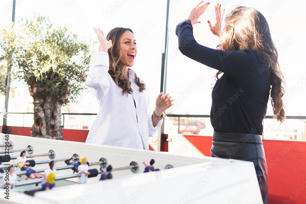 Happy girlfriends giving high five after foosball match Stock Photo ...