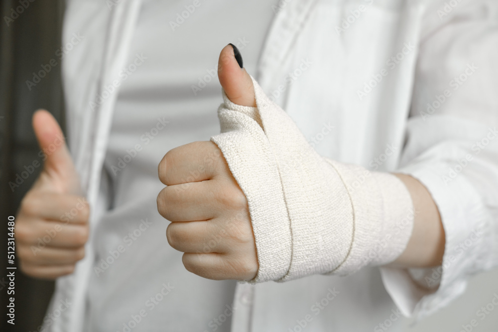 A girl with a bandaged hand shows a thumbs up, a hand injury, an ...