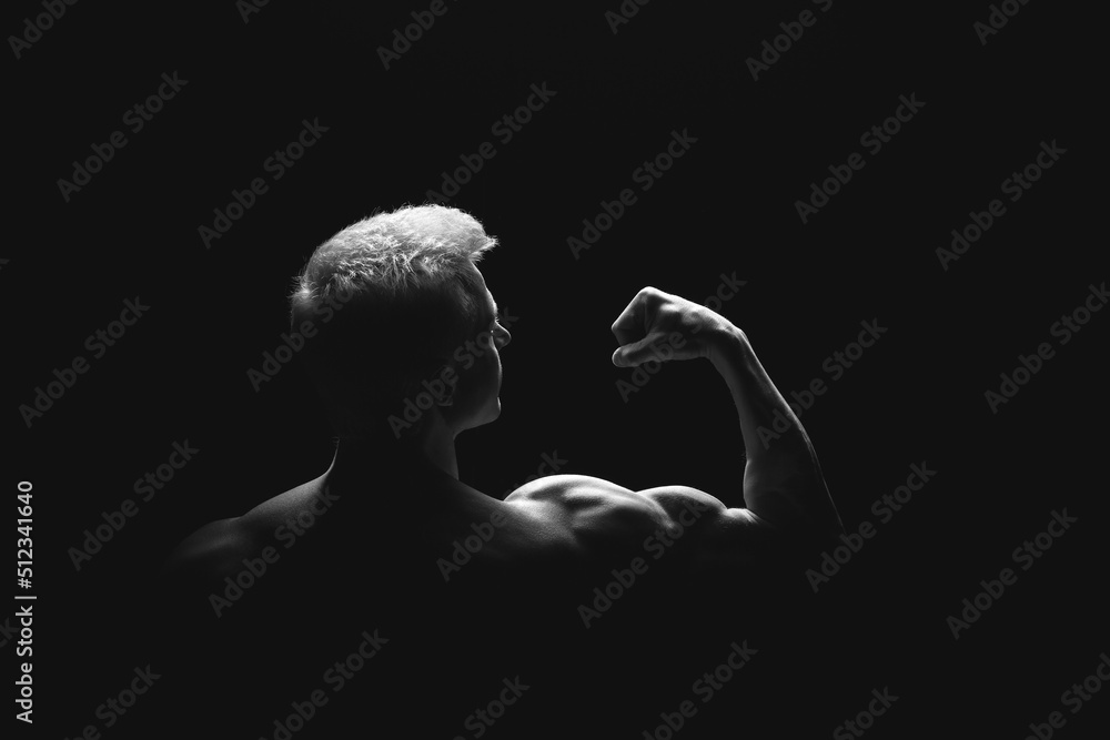 Handsome power athletic man in dramatic light. Strong bodybuilder with ...