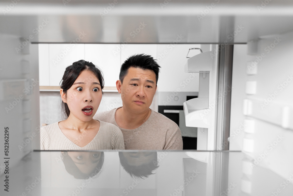 Shocked asian couple looking inside empty fridge at home Stock Photo ...