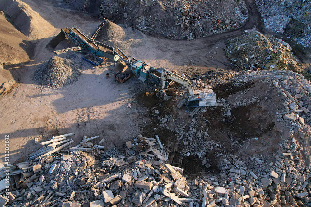 Excavator at landfill the load concrete waste in a mobile jaw crusher ...
