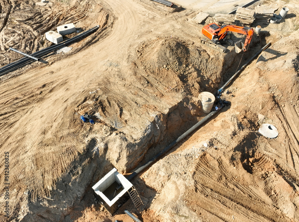 Sewage drainage system mounting at construction site. Excavator during ...